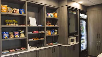 Uma área de máquinas de venda automática com opções de lanches e um refrigerador.