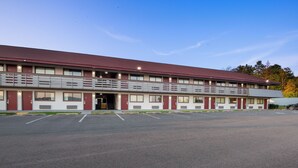 Um motel com vários andares, teto plano, área de estacionamento coberta e céu claro.