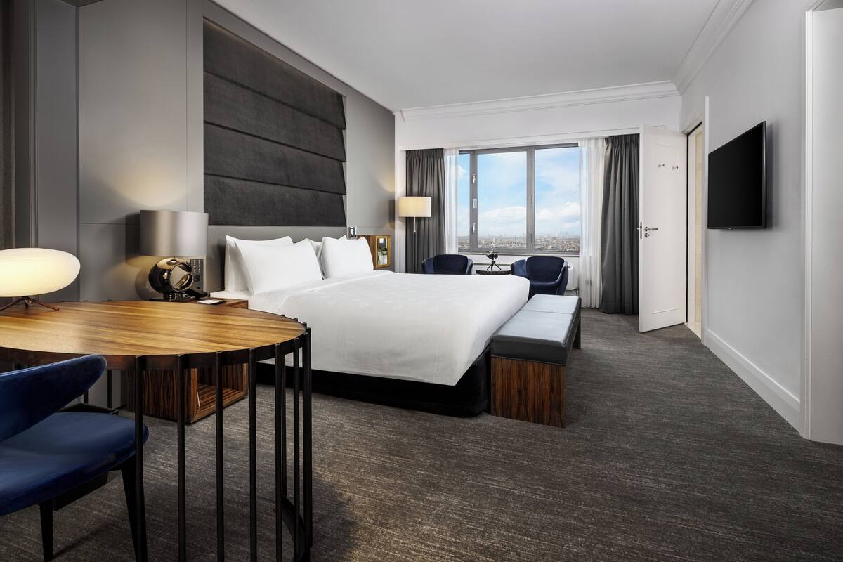Quarto de hotel moderno com uma cama grande, uma escrivaninha e uma TV.