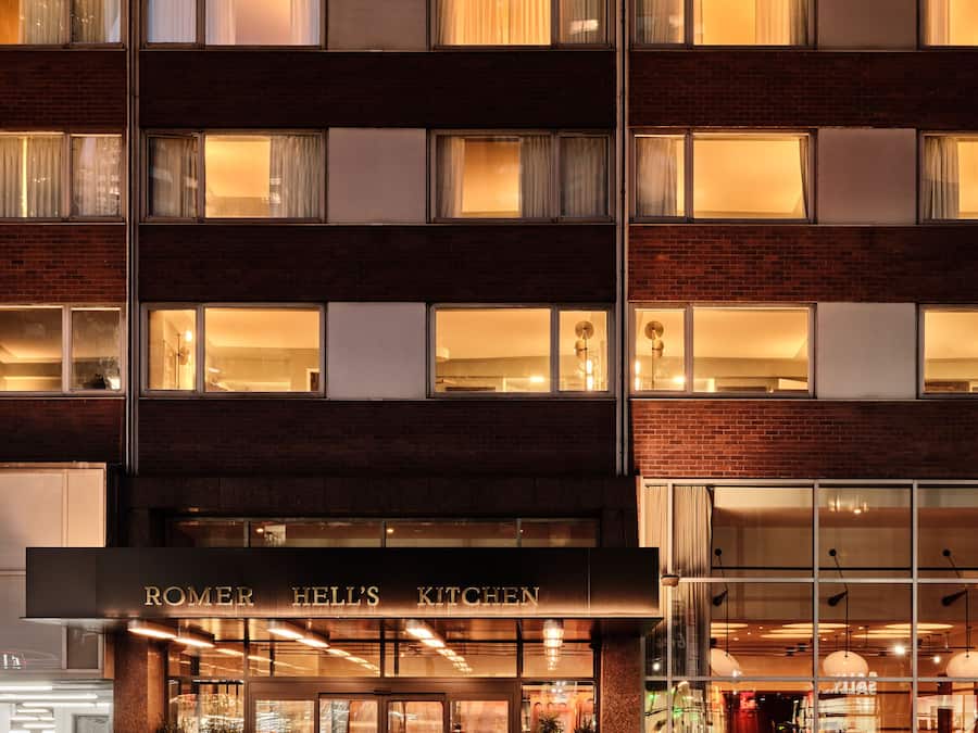 Um edifício de vários andares com um restaurante chamado "ROMER HELL'S KITCHEN" no nível térreo.