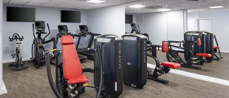Academia com máquinas de cardio, equipamentos de musculação e espelhos nas paredes.