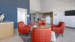 Um hall moderno com cadeiras xadrez vermelhas, um balcão de recepção e uma parede estampada.