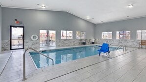 Piscina interna com parede de mármore, uma cadeira azul e um sinal de saída.