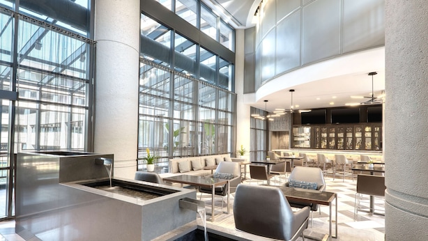 Um lobby moderno com uma fonte central, áreas de estar e um bar.