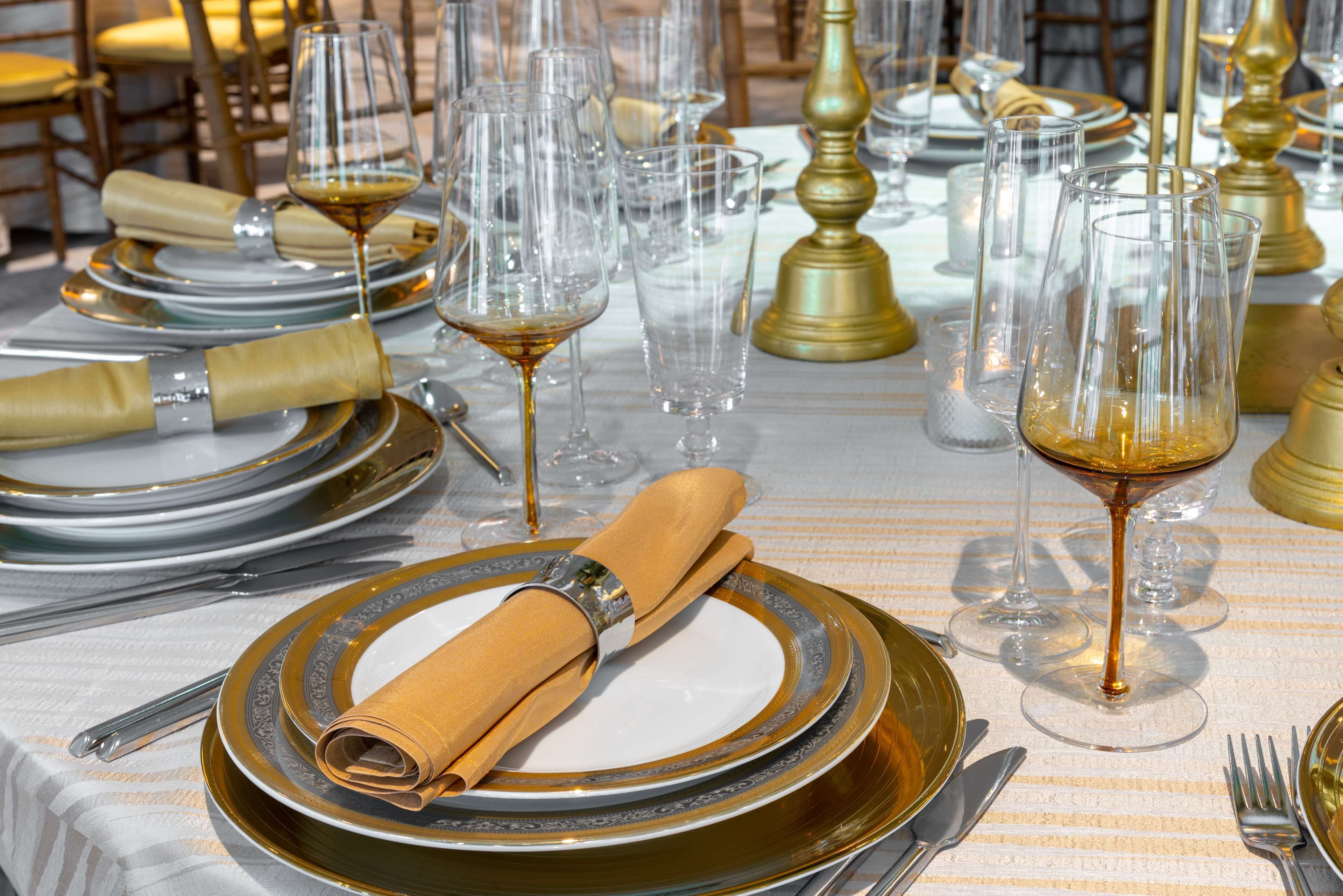 Mesa posta para um jantar formal, com vários pratos, copos e talheres.