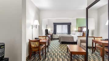 Quarto de hotel com cama, escrivaninha, cadeira, mesa, luminária e espelho.
