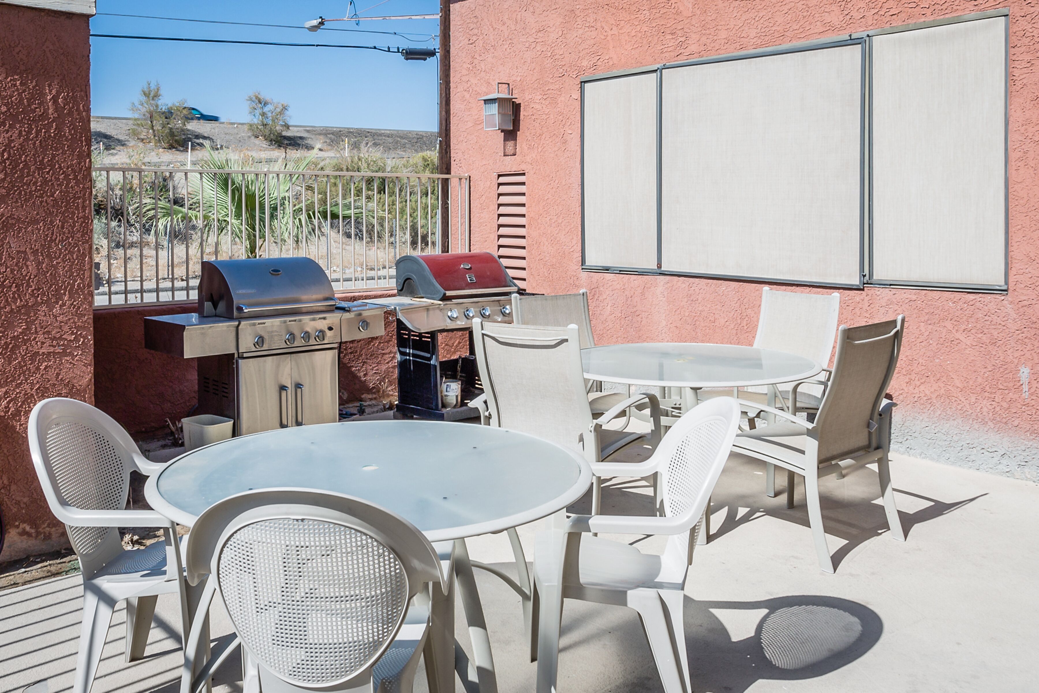 Um pátio externo com churrasqueira, uma mesa e cadeiras.