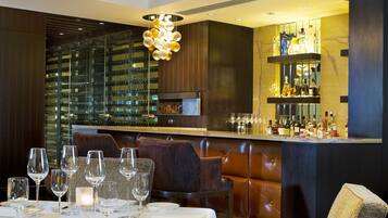 Um restaurante com área de bar, teto de madeira e disposição de mesas e cadeiras.
