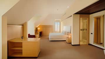 Quarto de hotel com escrivaninha, cama e área de estar.