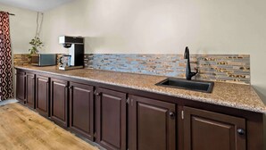 Uma cozinha moderna com armários marrom escuro, bancada de granito, pia embutida e backsplash com mosaicos.