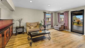 Uma sala de estar moderna com piso de madeira, um sofá, uma mesa de centro e uma cortina estampada.