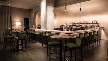 Uma área de bar com diversas opções de assento, balcão e variedade de garrafas.