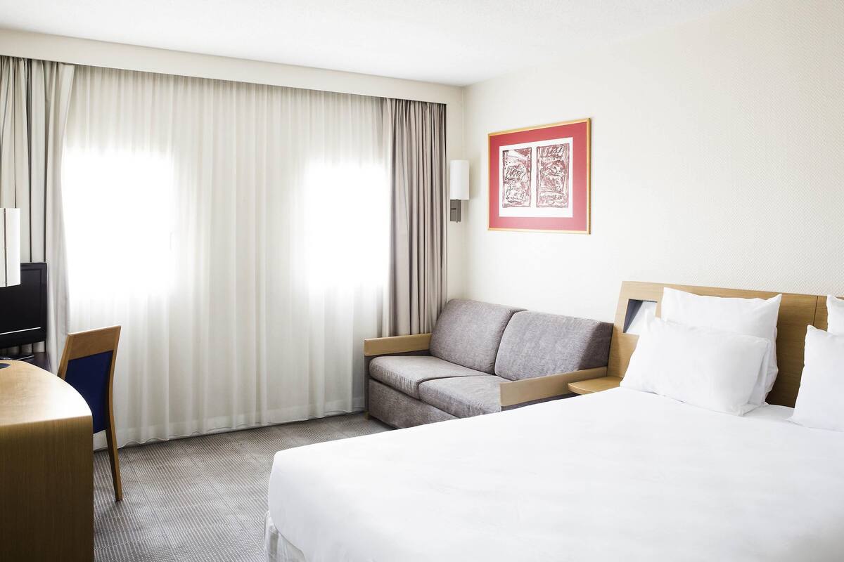 Quarto de hotel com cama, sofá, escrivaninha e cadeira.