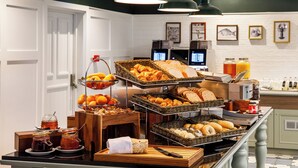 Um buffet de café da manhã com pães, doces e frutas.