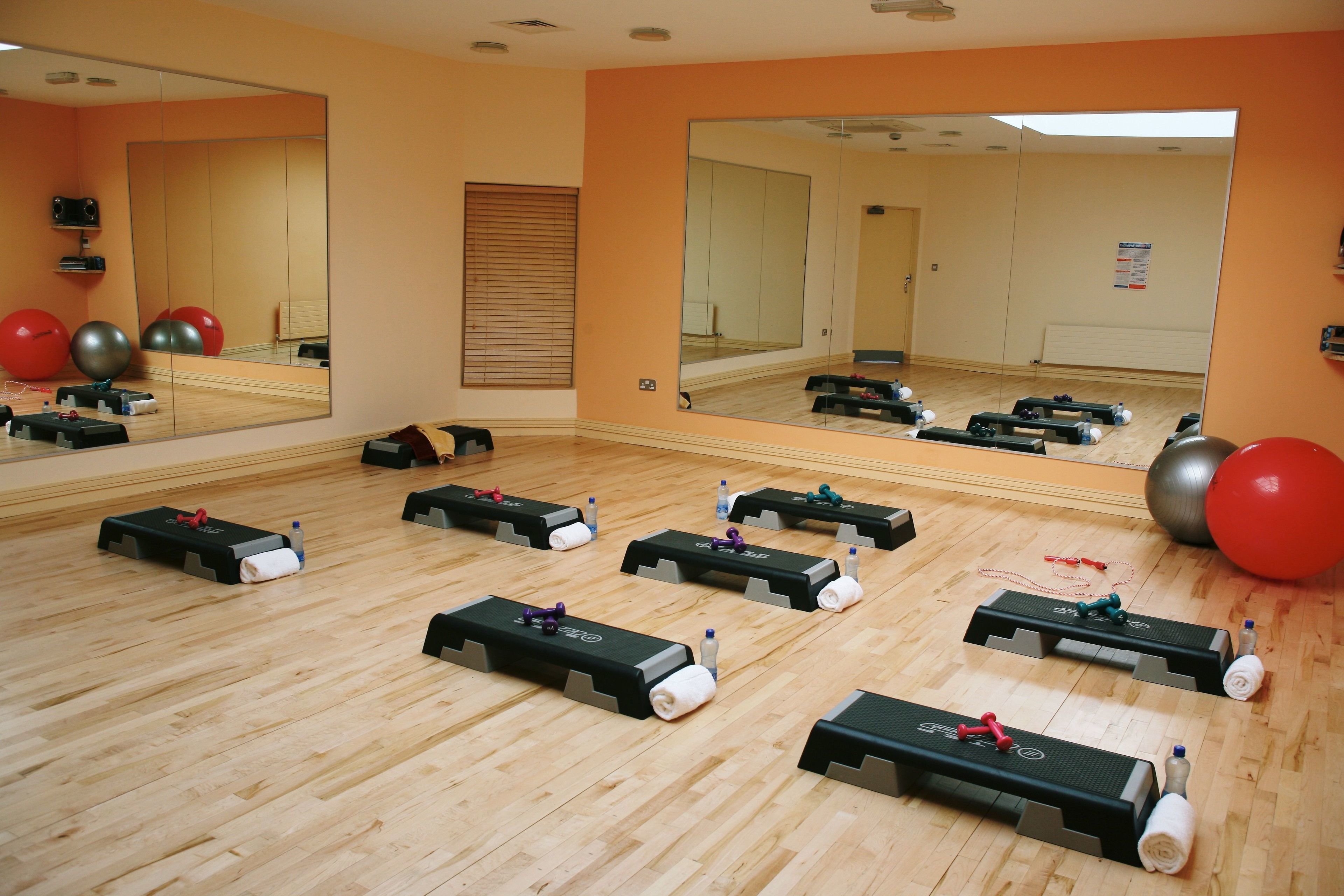 Uma academia com equipamentos de ginástica, espelhos e bolas de exercício.