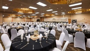 Uma sala de banquetes com mesas redondas, cadeiras brancas e toalhas de mesa pretas.