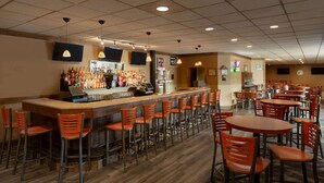 Uma área de bar com balcão, banquetas e mesas com cadeiras.