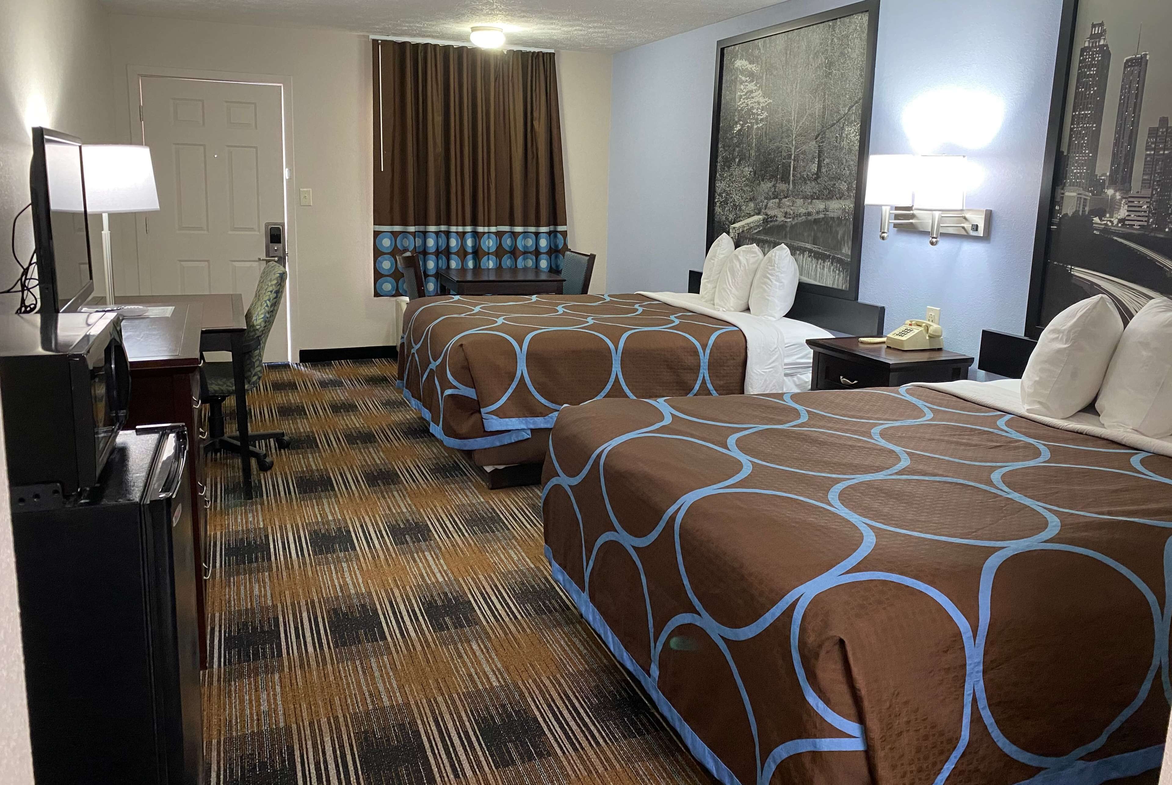 Quarto de hotel com duas camas, uma escrivaninha, uma cadeira, um computador e vista para a cidade.