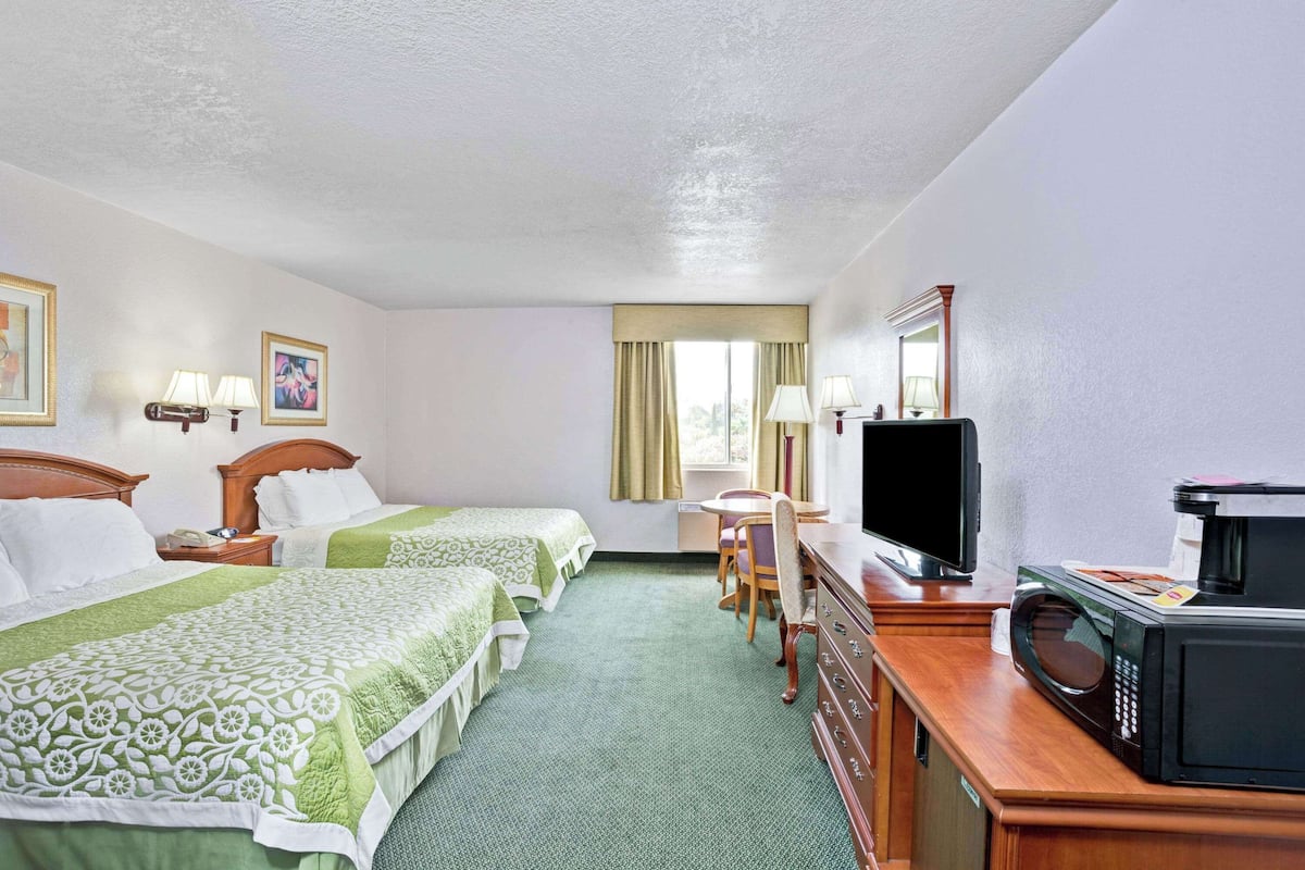 Quarto de hotel com duas camas, uma mesa, televisão e micro-ondas.