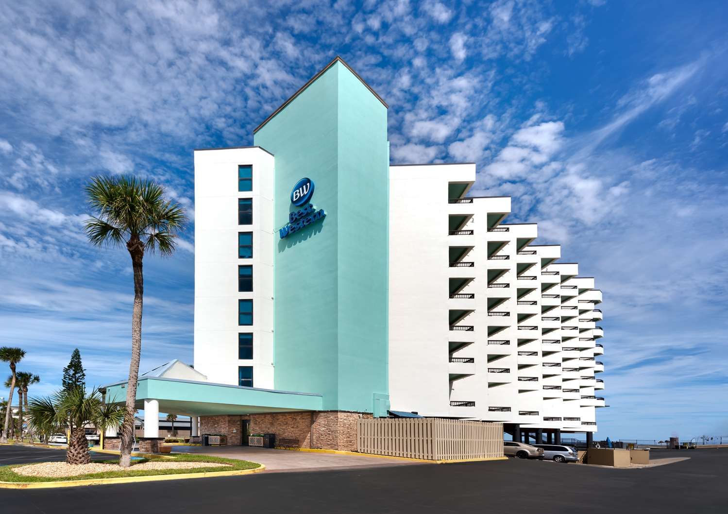 Um hotel com uma placa chamativa da 'Best Western', vários andares e um estacionamento.