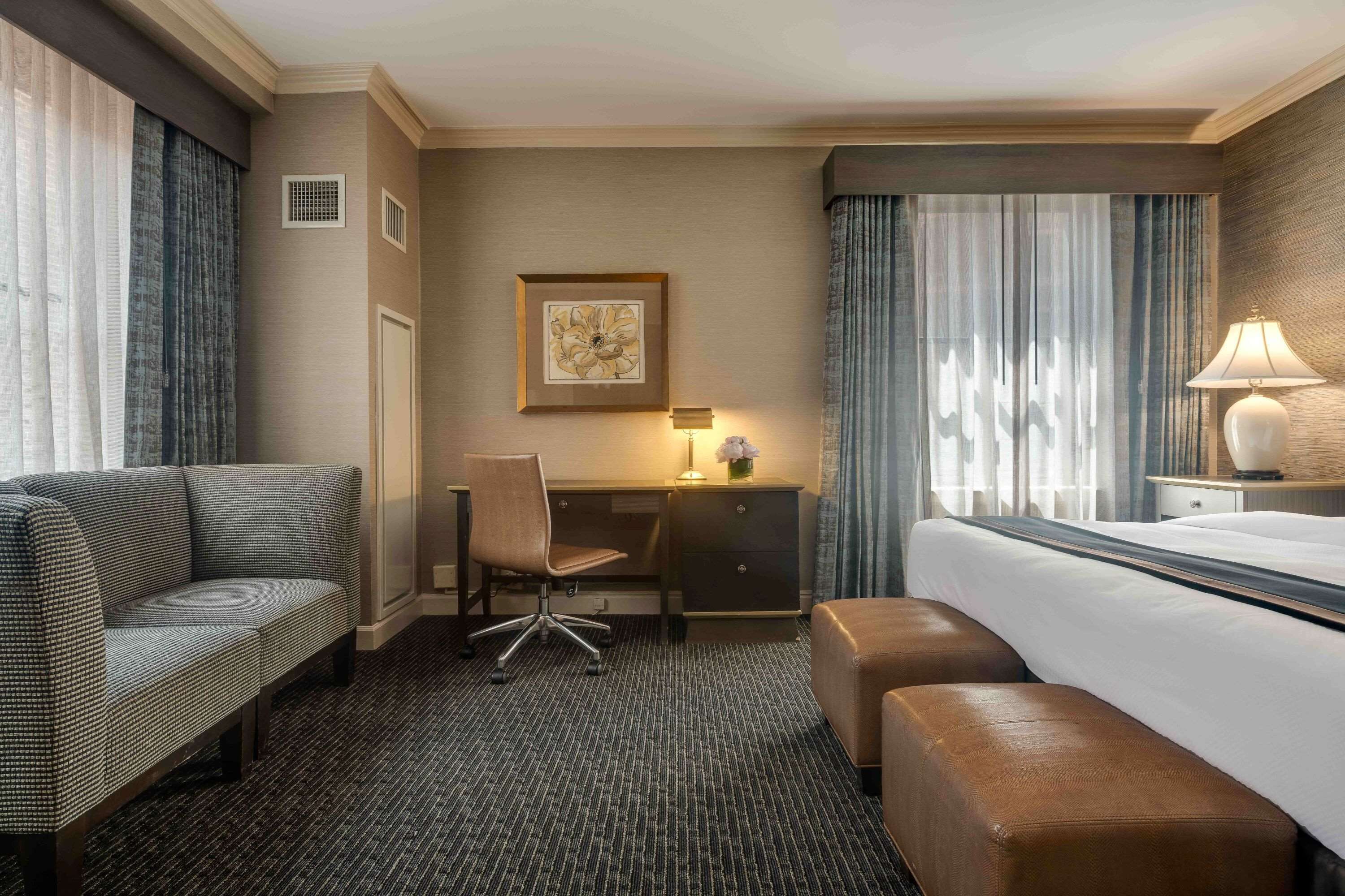 Quarto de hotel com sofá, escrivaninha, cadeira e cama.