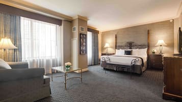 Quarto de hotel com cama, sofá, mesa pequena e abajur.