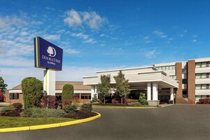 Um hotel DoubleTree by Hilton com céu claro, gramado bem cuidado e fachada de edifício moderna.