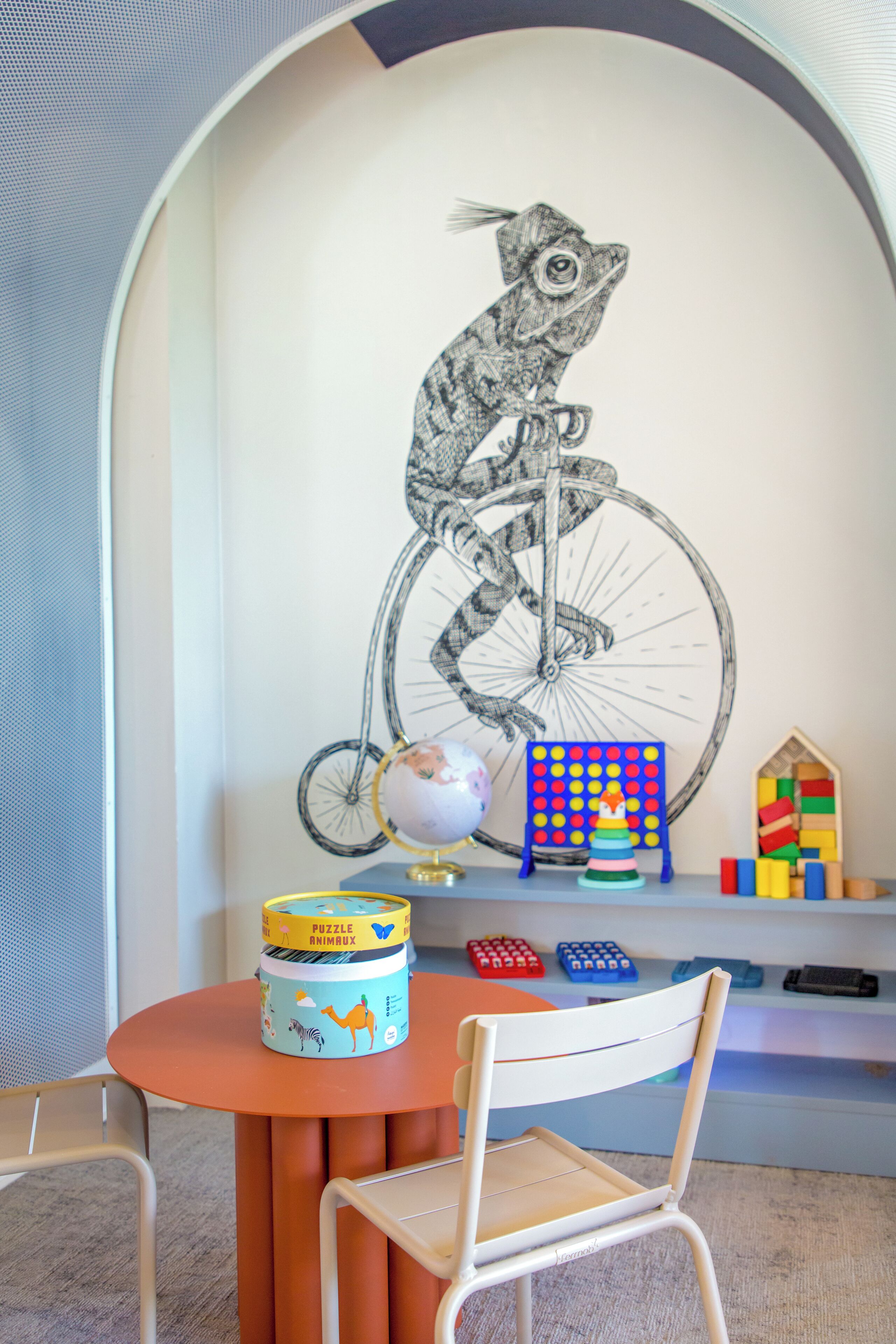 Espaço de recreação infantil com painel de parede, um globo, brinquedos de encaixe e uma casinha de brinquedo.