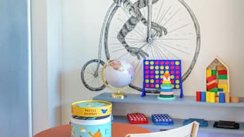 Espaço de recreação infantil com painel de parede, um globo, brinquedos de encaixe e uma casinha de brinquedo.