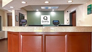 Balcão de recepção de hotel com uma placa que diz 'Quality by Choice Hotels'.