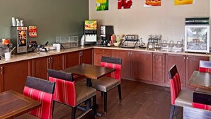 Restaurante com balcão, mesas e diversos equipamentos de preparo de alimentos.