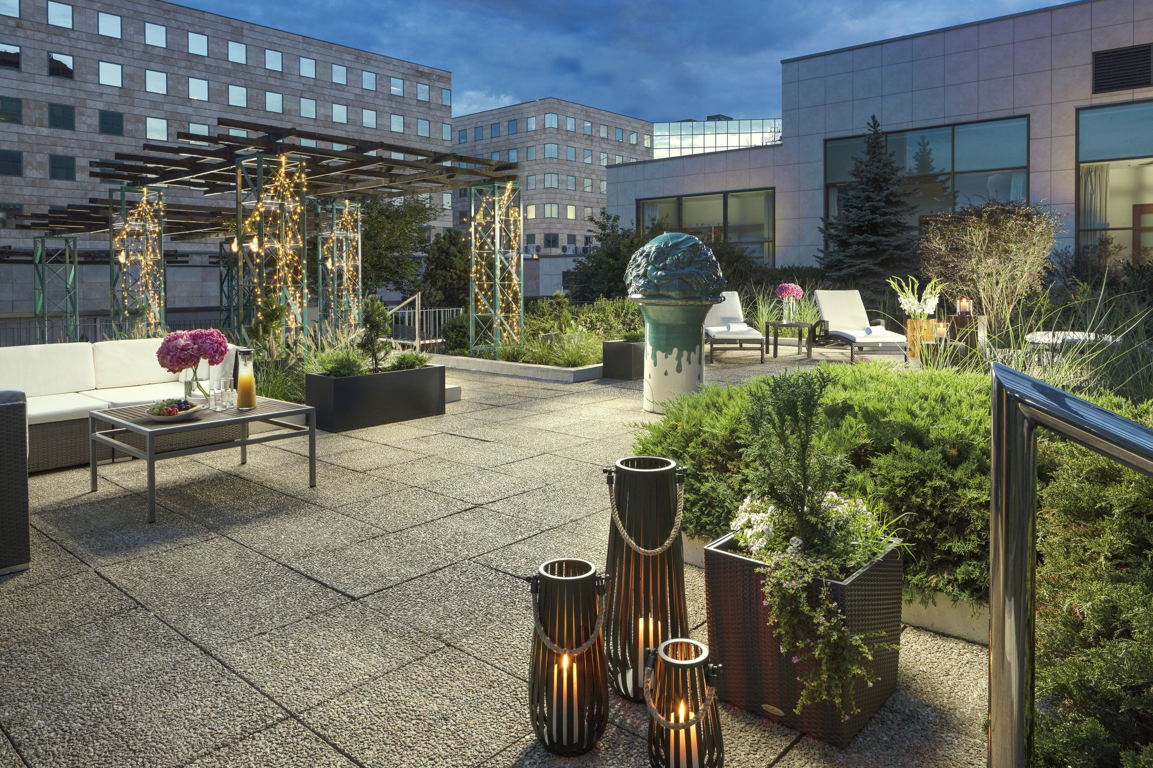 Terraço no telhado com área de estar ao ar livre, plantas em vasos e iluminação decorativa.