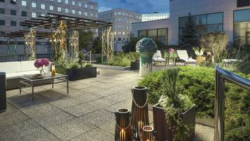 Terraço no telhado com área de estar ao ar livre, plantas em vasos e iluminação decorativa.