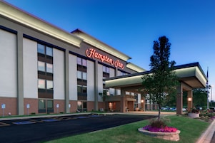Um hotel Hampton Inn com fachada moderna, entrada coberta e estacionamento.