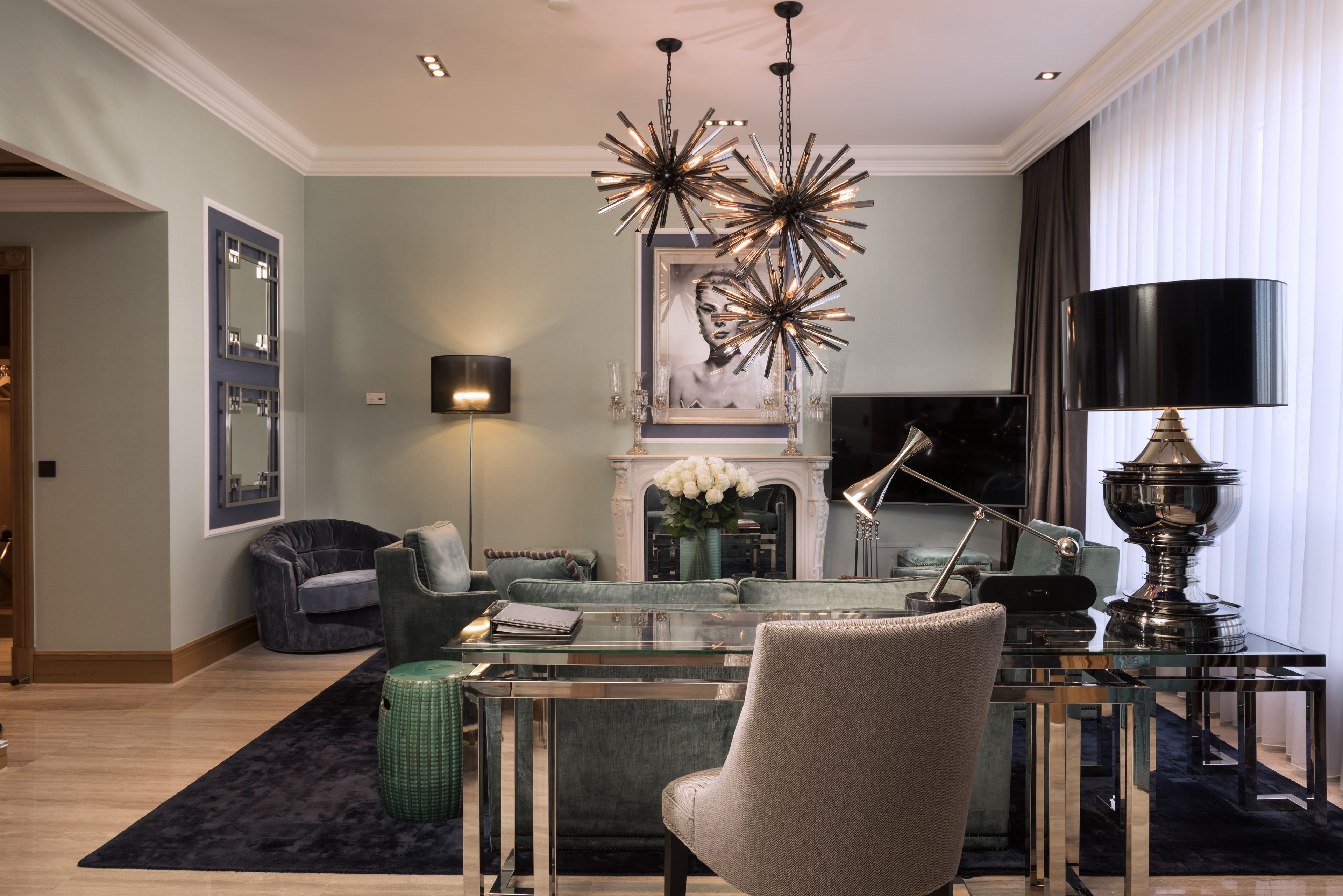 Uma sala de estar moderna com uma mesa de centro de vidro, um sofá confortável, uma luminária elegante e um lustre decorativo.