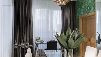 Uma sala de estar moderna com uma mesa de centro de vidro, sofás brancos, um espelho grande e um lustre.
