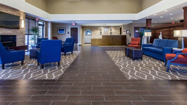Um hall amplo com balcão de recepção, assentos em azul e vermelho, e piso estampado.