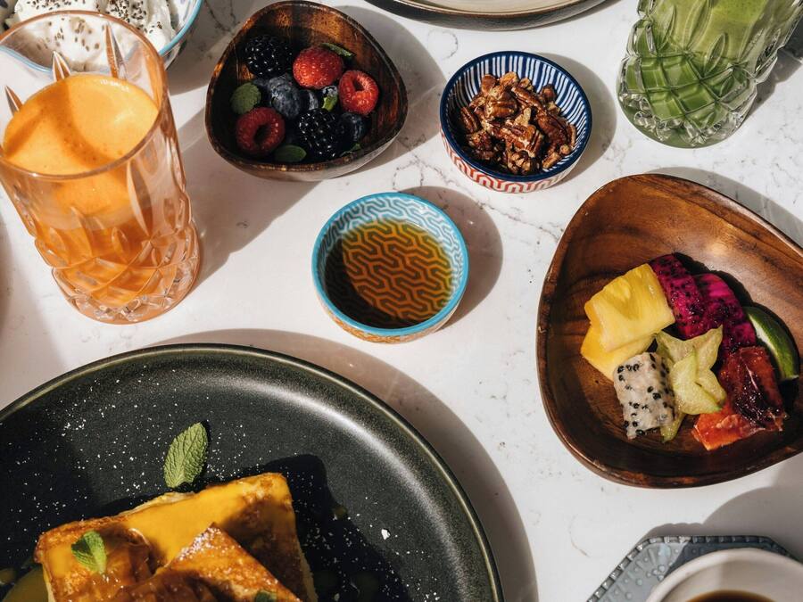 Mesa posta para o café da manhã com panquecas, frutas e bebidas.