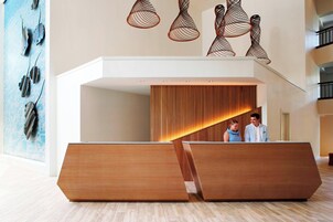 Uma moderna receção com acabamento em madeira, teto inclinado e iluminação pendente.