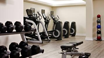 Uma academia com equipamentos de ginástica, incluindo halteres, um banco e aparelhos de cardio.