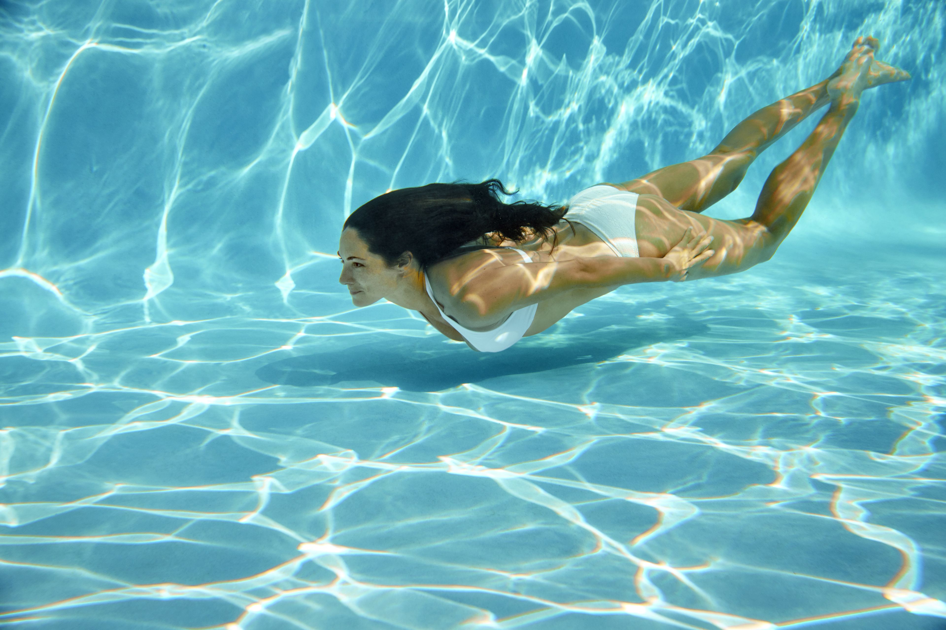 Uma pessoa nadando em uma piscina com água cristalina.