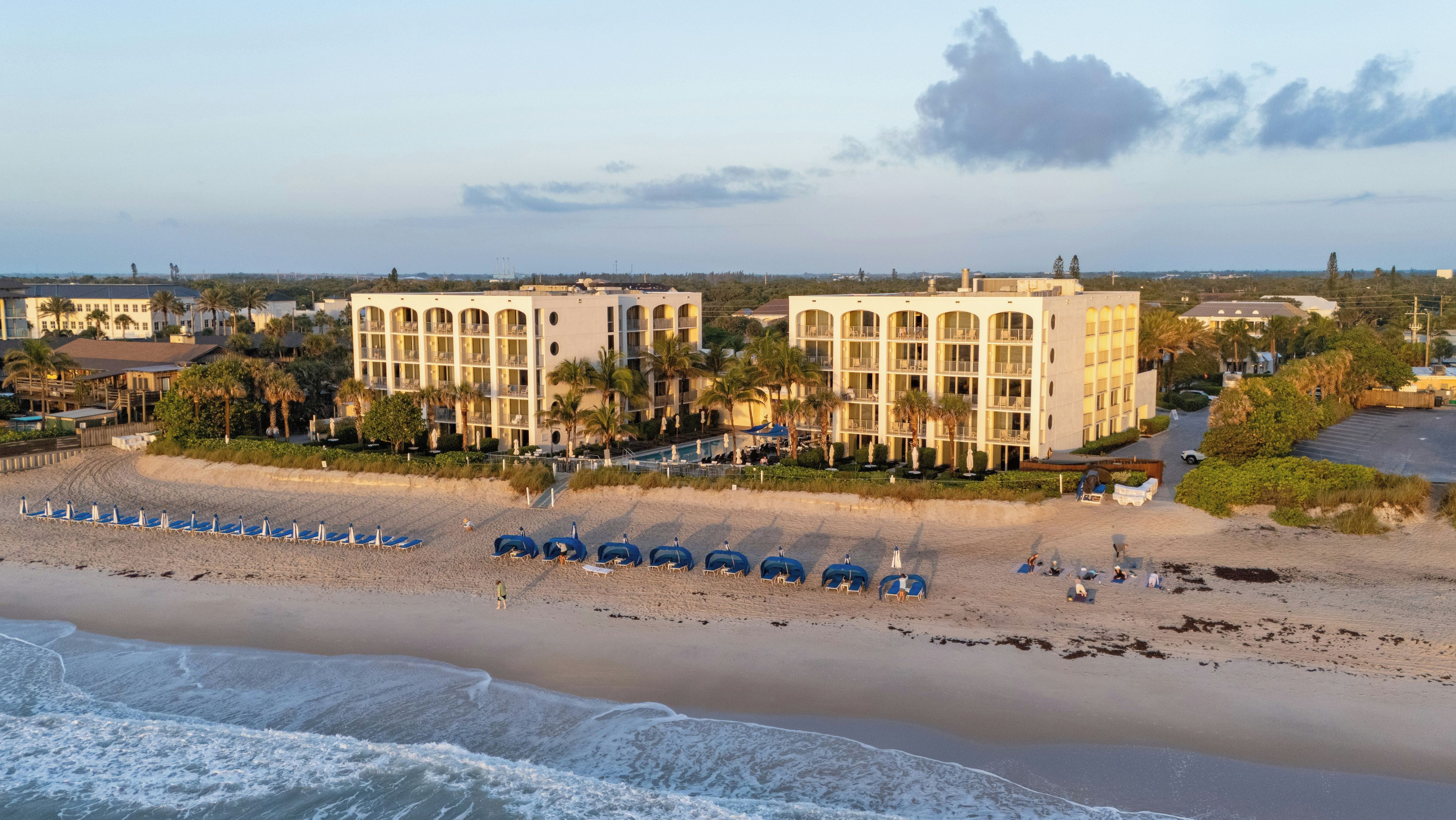Hotel à beira-mar com vários edifícios, uma praia de areia e área de piscina.