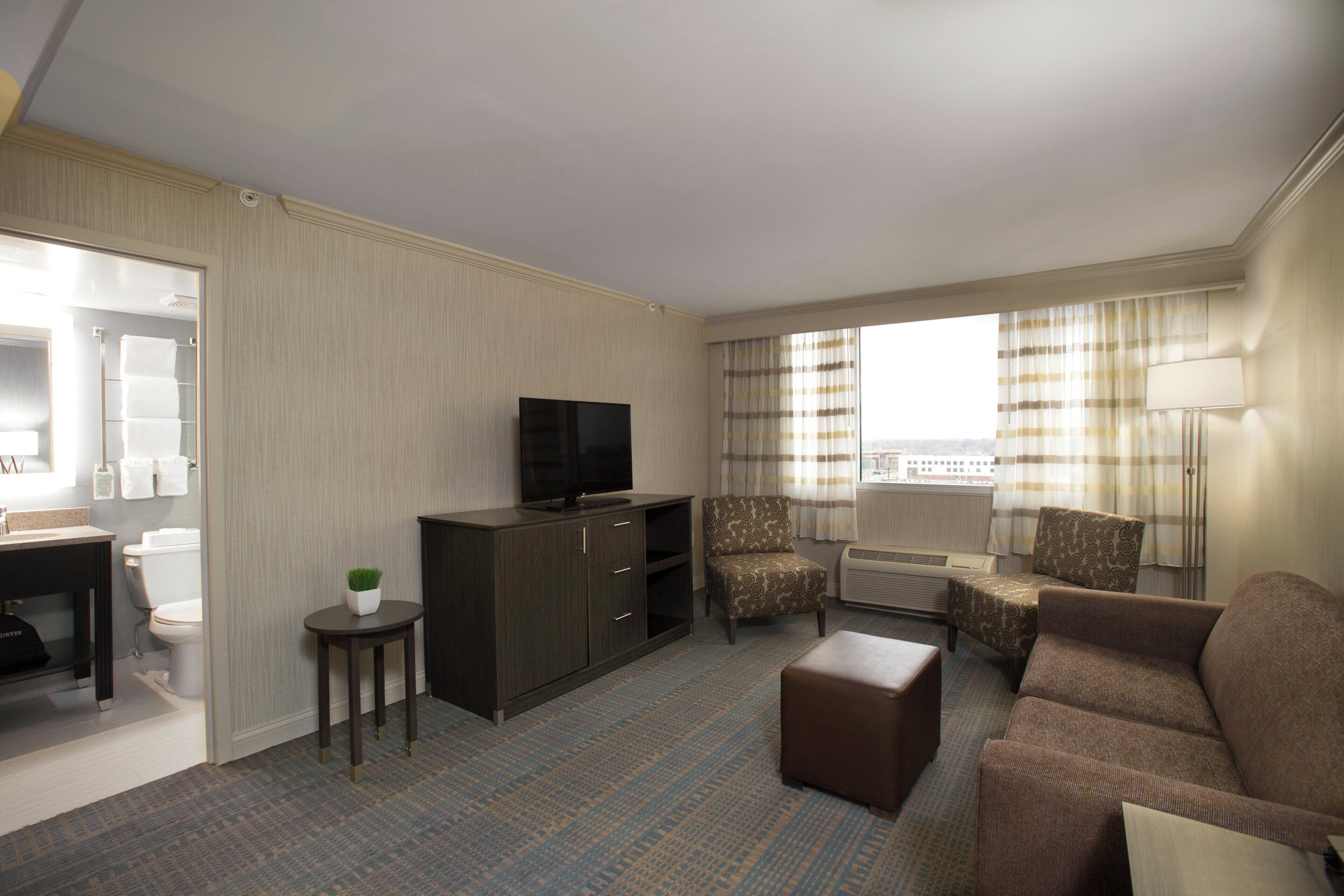 Quarto de hotel com televisão, área de estar e vista para a cidade.