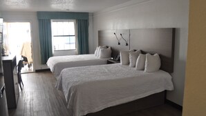 Quarto de hotel com duas camas, uma escrivaninha e uma cadeira.