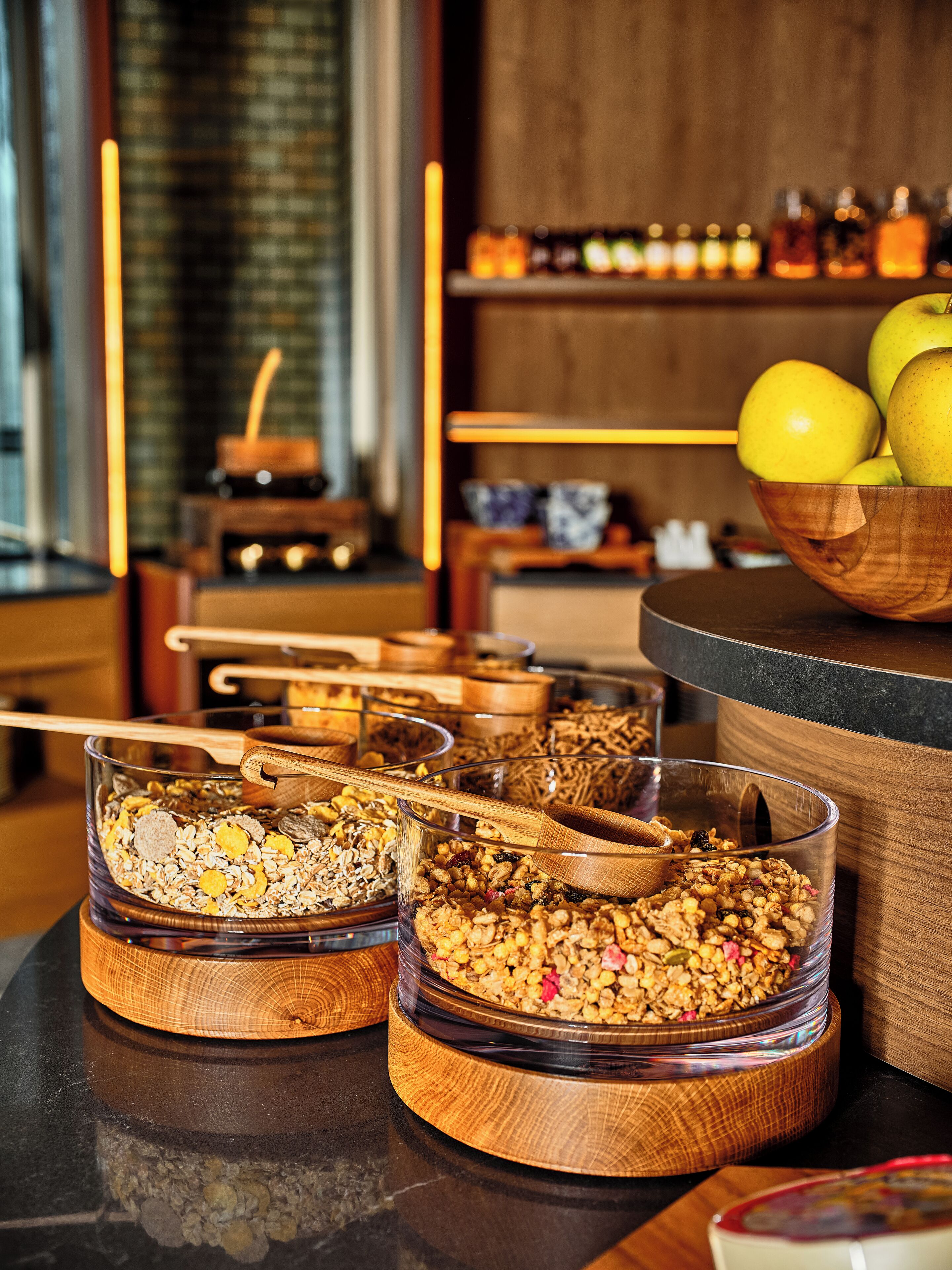 Um buffet com diversos alimentos em tigelas de madeira e recipientes de vidro.