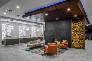 Um hall moderno com balcão de atendimento, sofás, lareira e uma parede decorativa.