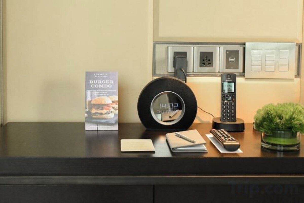 Balcão de recepção de hotel com menu, relógio, telefone e uma pequena planta.
