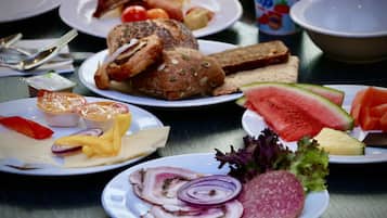 Uma mesa com diversos alimentos, incluindo pão, queijo, fatias de carne e legumes.