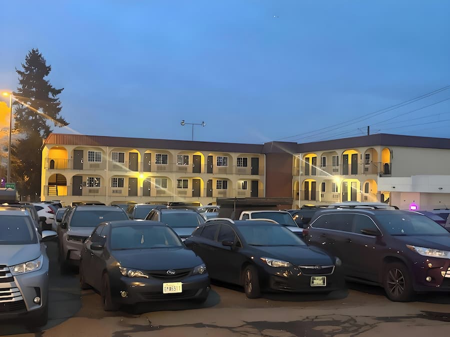 Um estacionamento com vários carros e um edifício com muitas varandas e janelas.