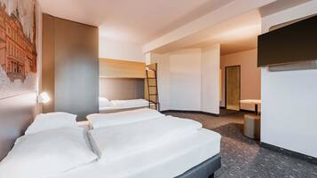 Quarto de hotel com duas camas, uma escada, banheiro e um mural na parede.